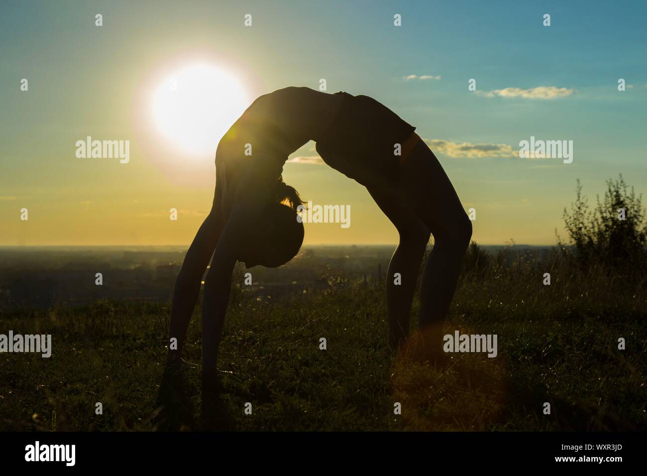 Silhouette of sporty woman practicing yoga in the park at sunset - drop ...