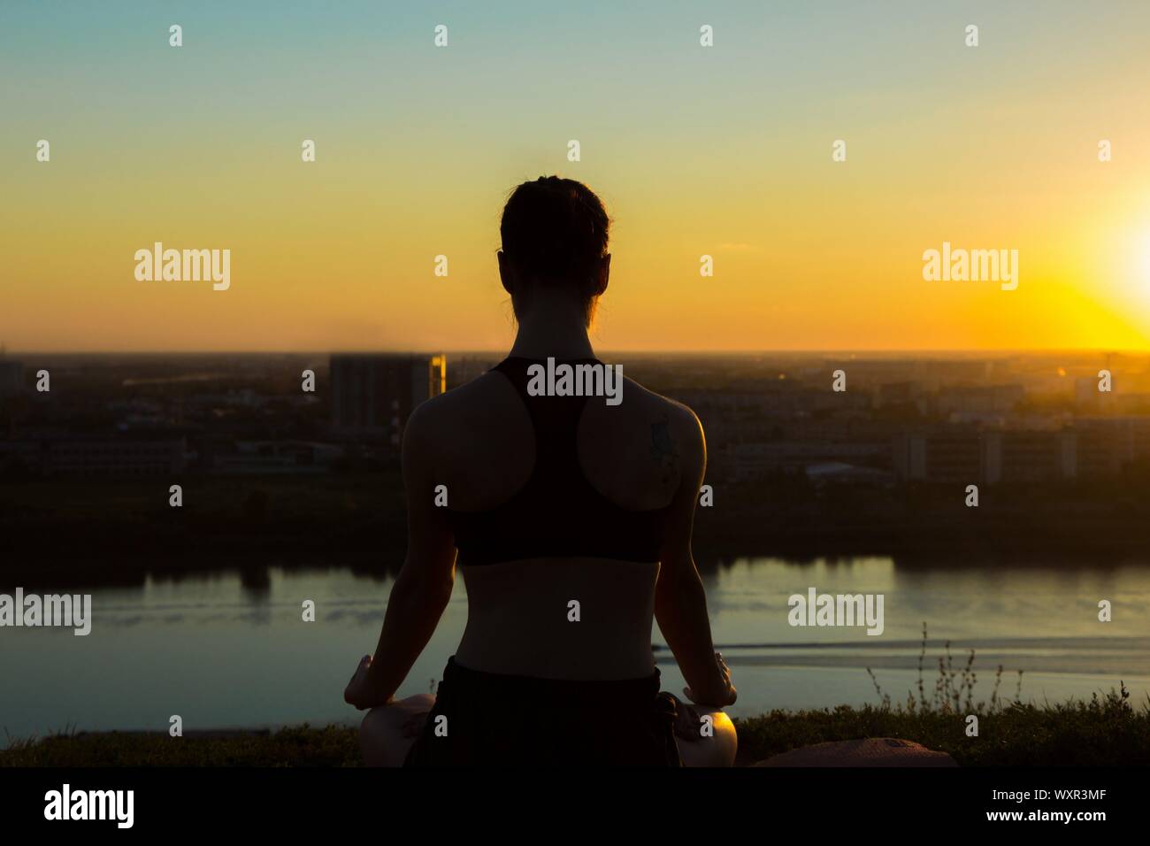 Sporty woman in lotus position in the park at sunset. Sunset light ...