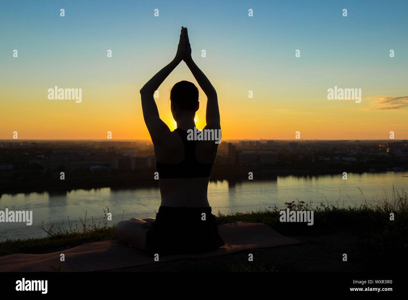Sporty woman practicing yoga in the park at sunset - sun salutation ...