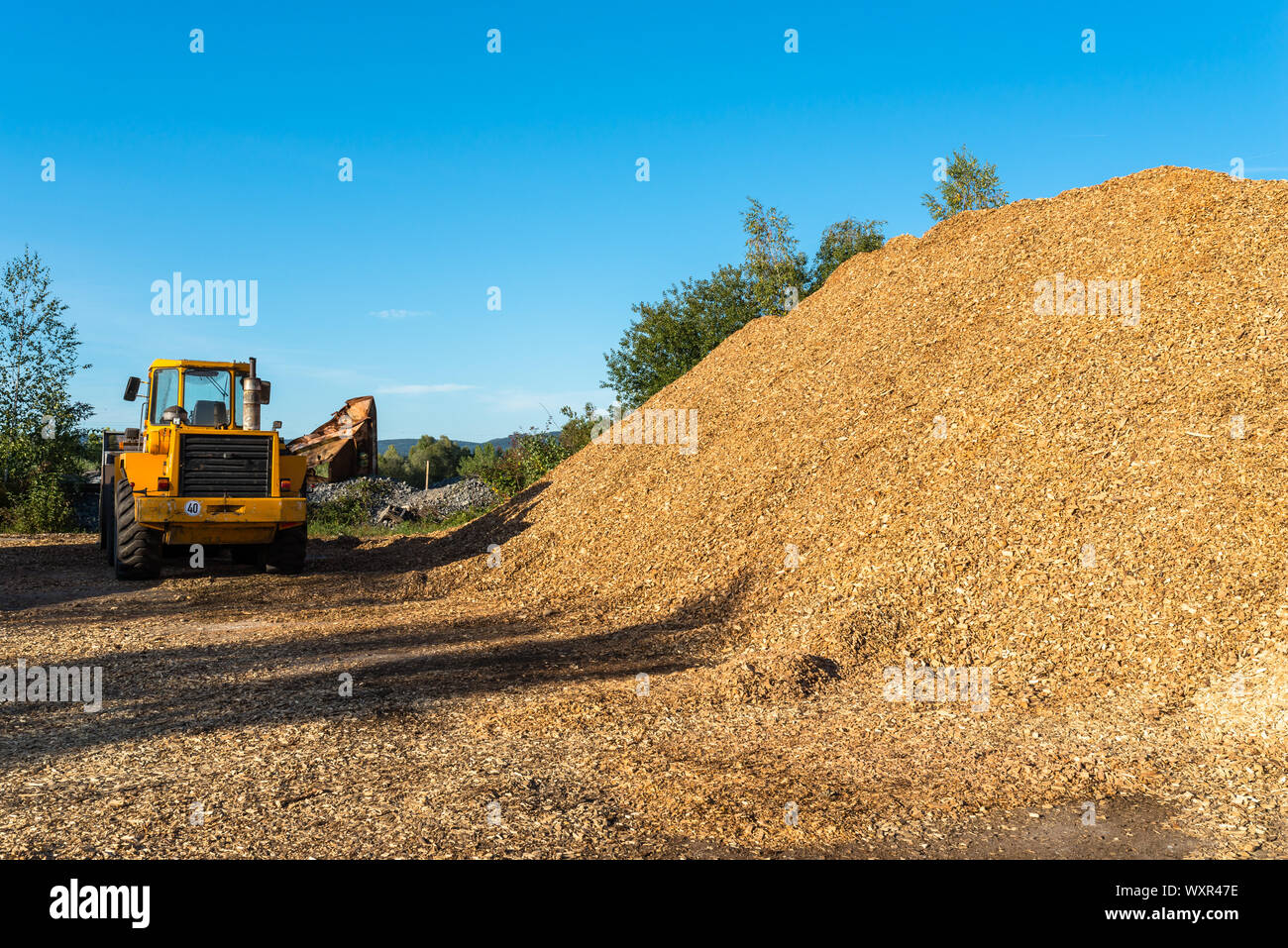 A large pile of wood chips lying on a square, with a blue sky in the ...