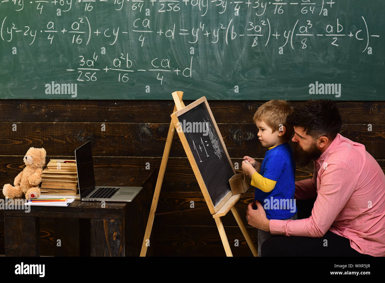 Pupil with teacher at school. Side view father and son learn arithmetic ...