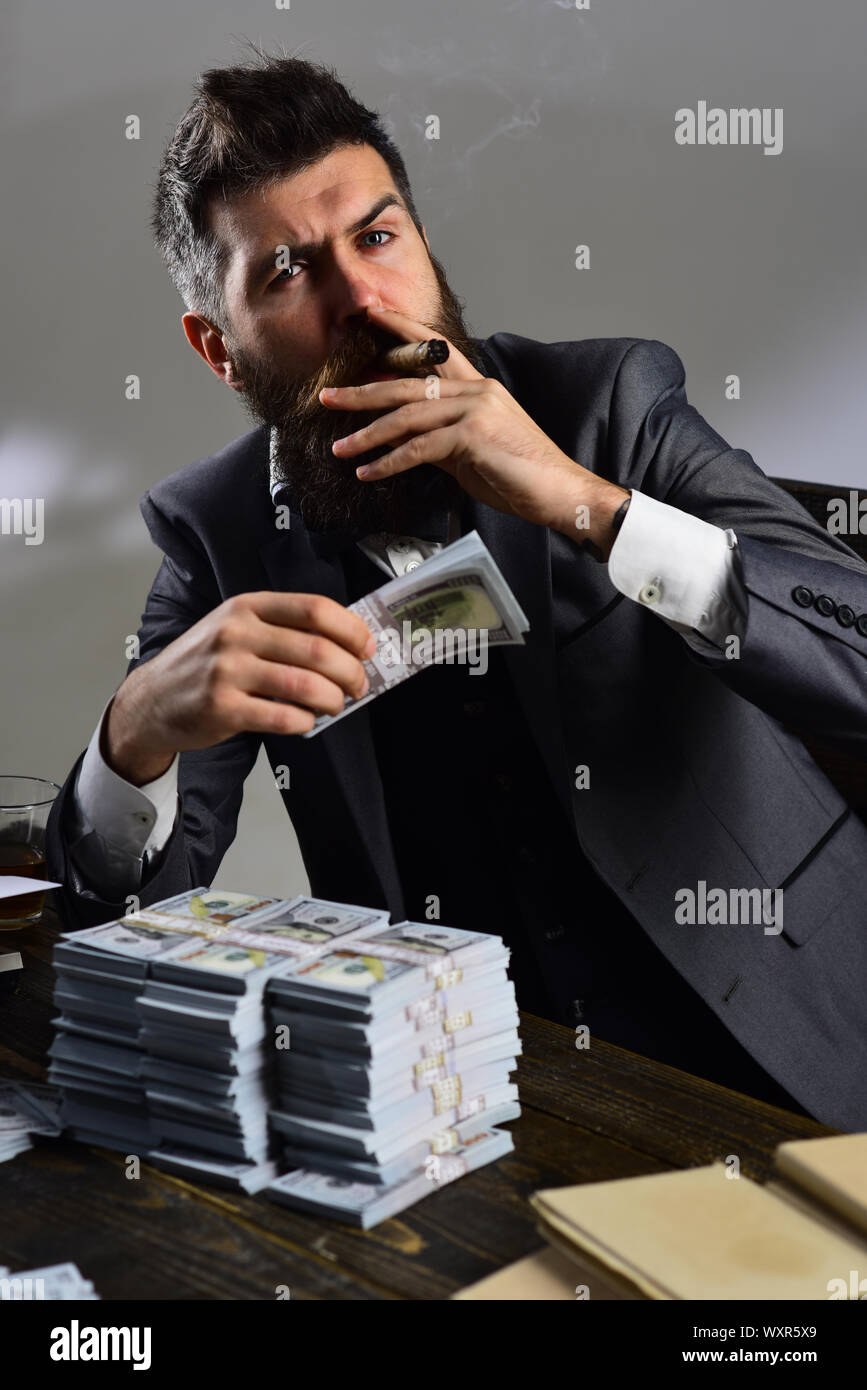 Man sitting at table with piles of money, counting profit. Illegal cash ...
