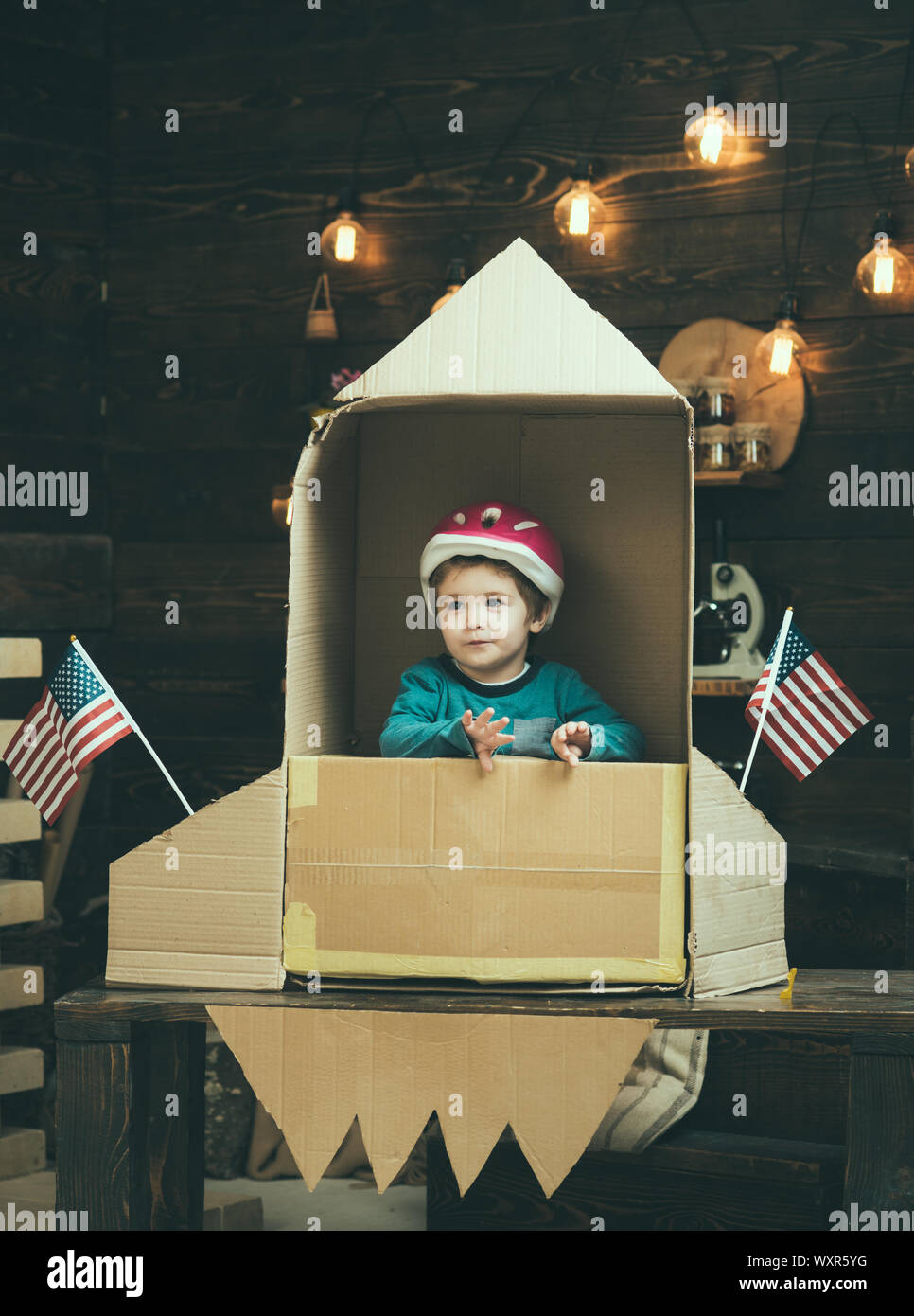 Kid in helmet sit in cardboard hand made rocket with usa flags. Child ...