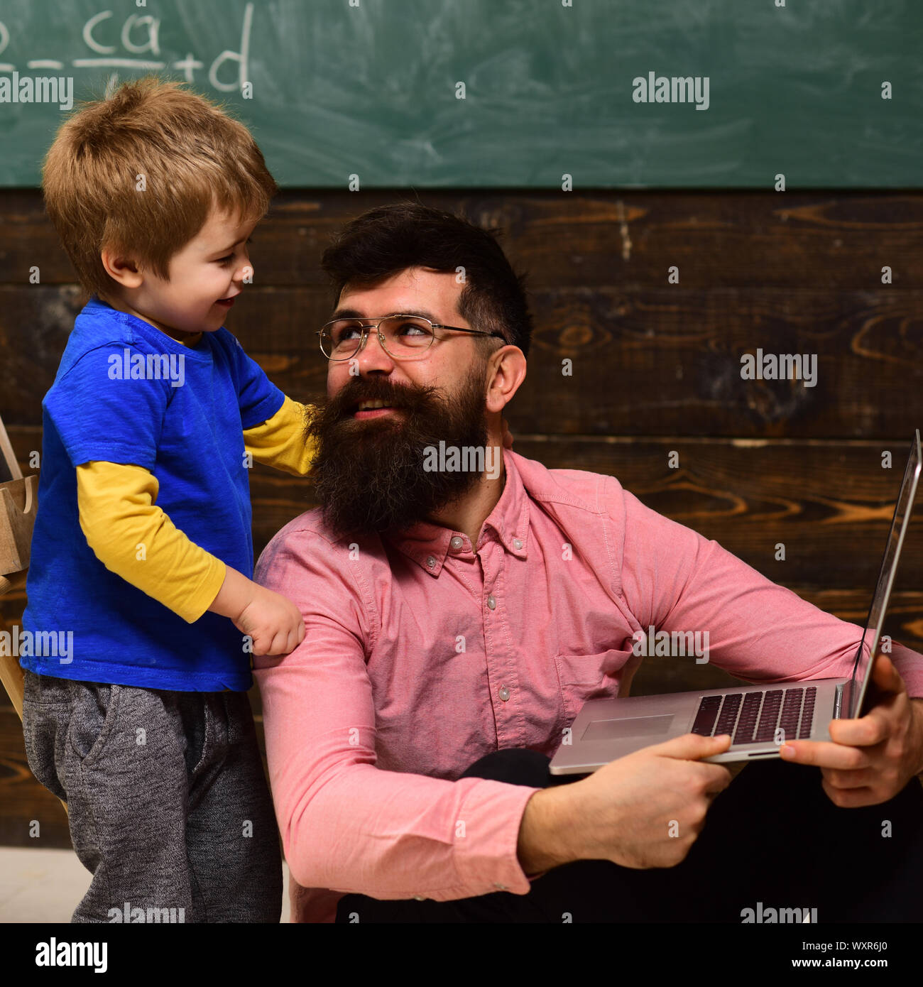 Smiling daddy teaching his boy computer skills. Father and son looking ...