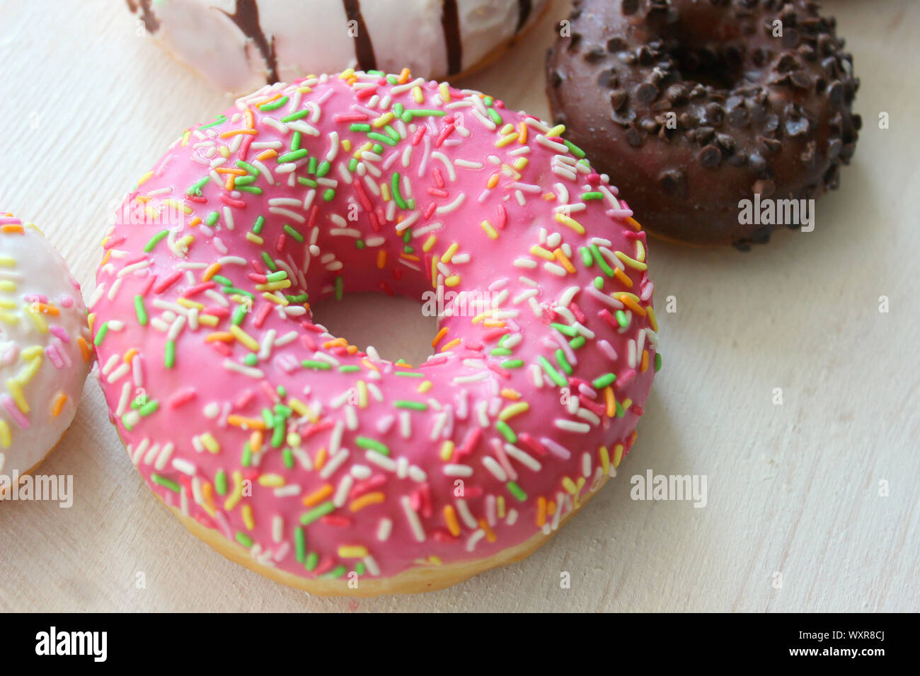 Pink doughnut with sprinkles on white textured background Stock Photo ...