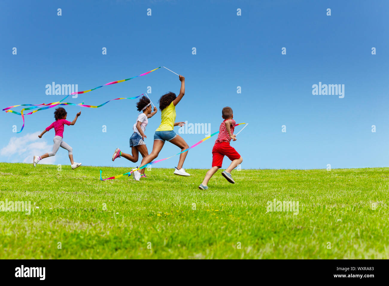 Group of kids run very fast with color ribbons Stock Photo - Alamy