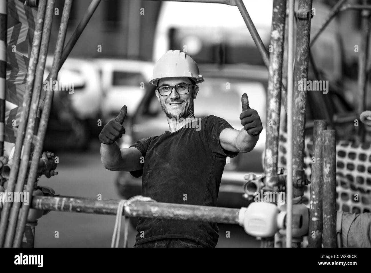 Young italian building worker, engineer smiling and showing thumb up ...