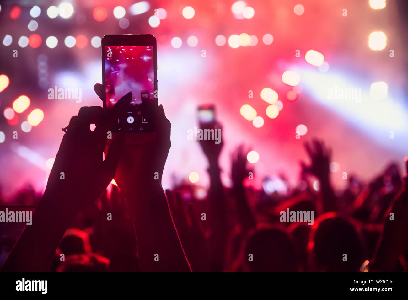 People taking photographs with touch smart phone during a music ...