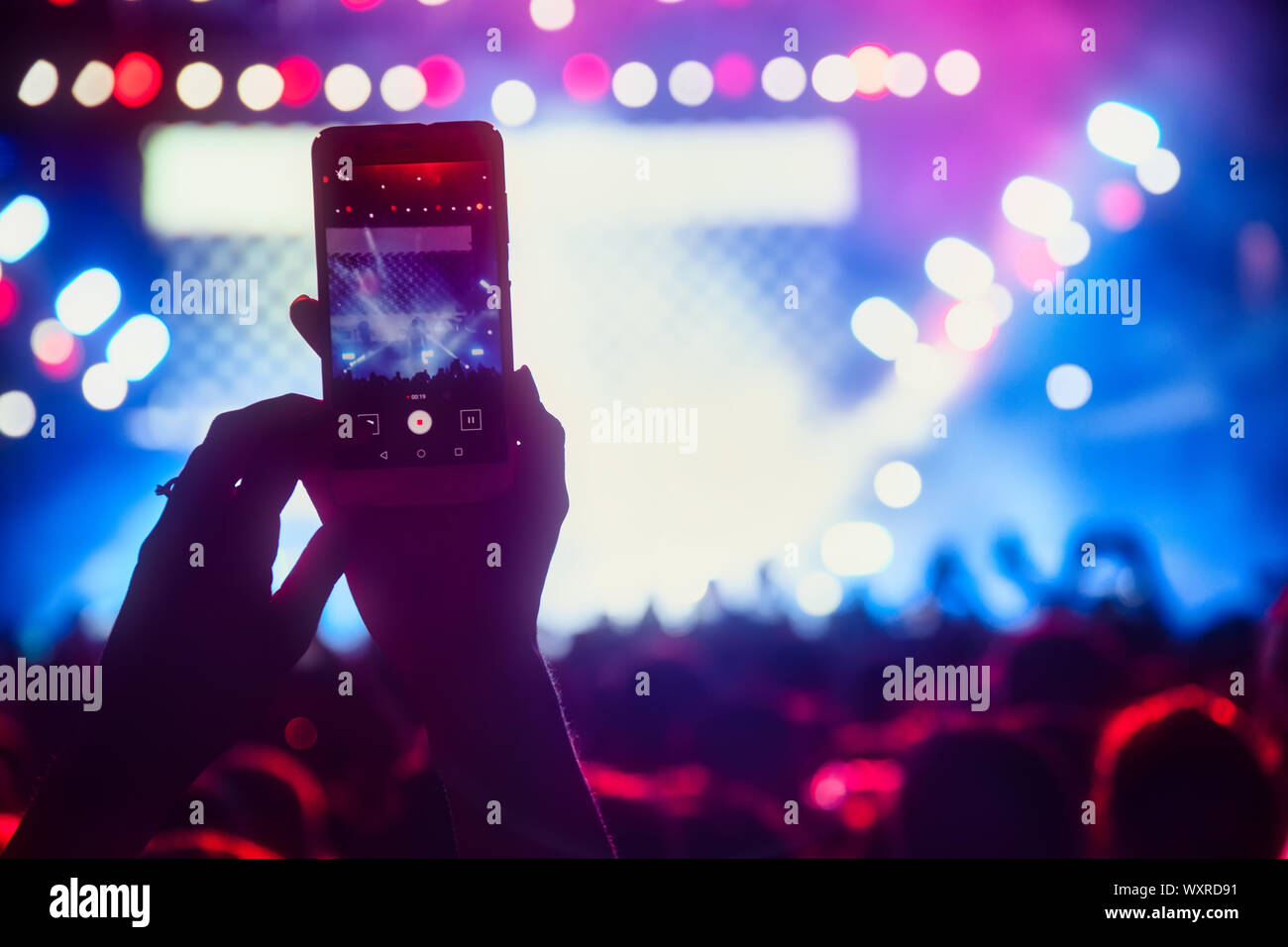 People taking photographs with touch smart phone during a music ...