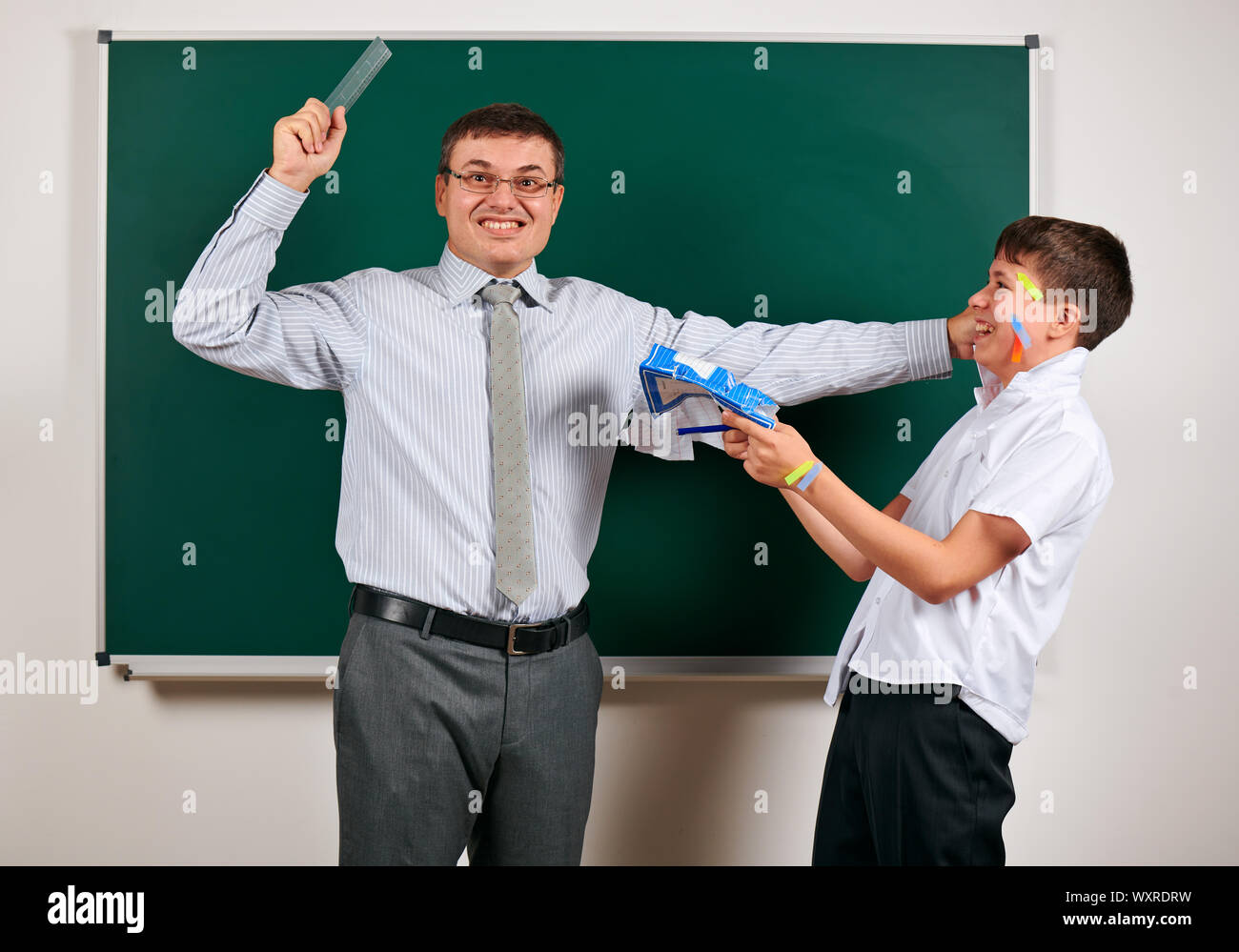 Portrait of a teacher catch the ear funny schoolboy with low discipline ...