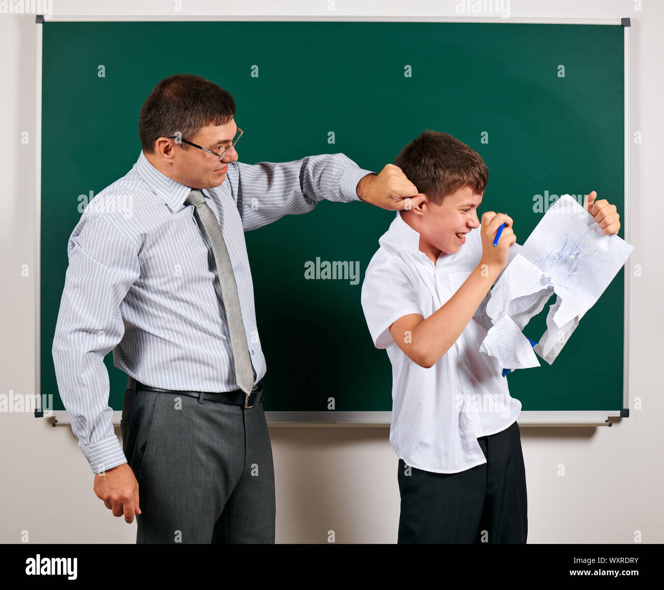 Portrait of a teacher catch the ear funny schoolboy with low discipline ...