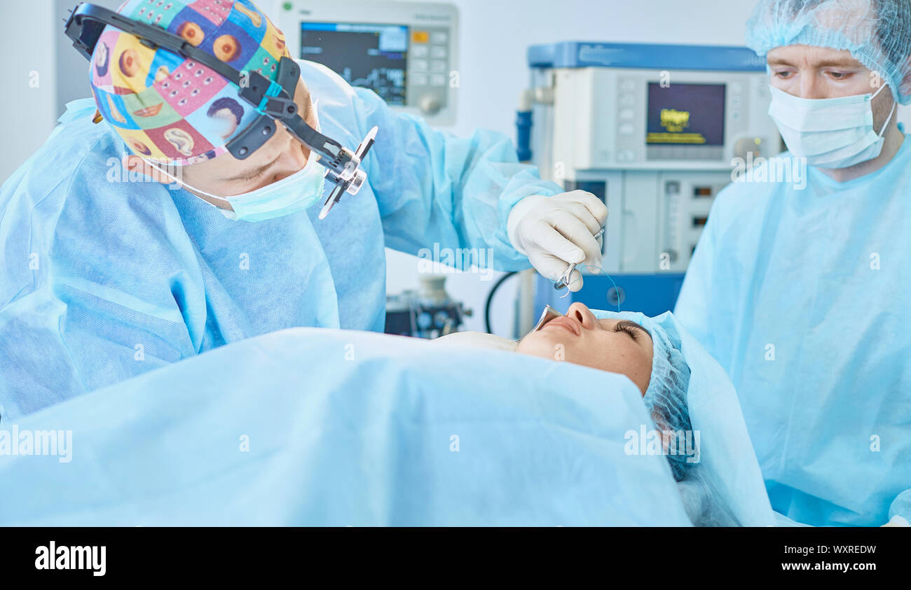Several doctors surrounding patient on operation table during their ...
