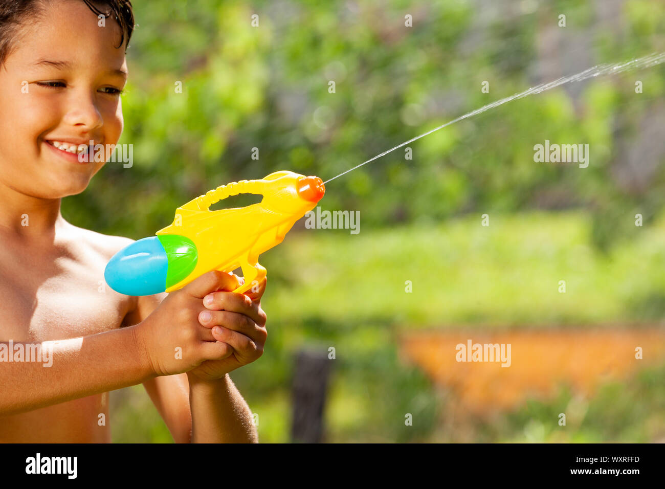 Little smiling happy boy shooting water gun Stock Photo - Alamy