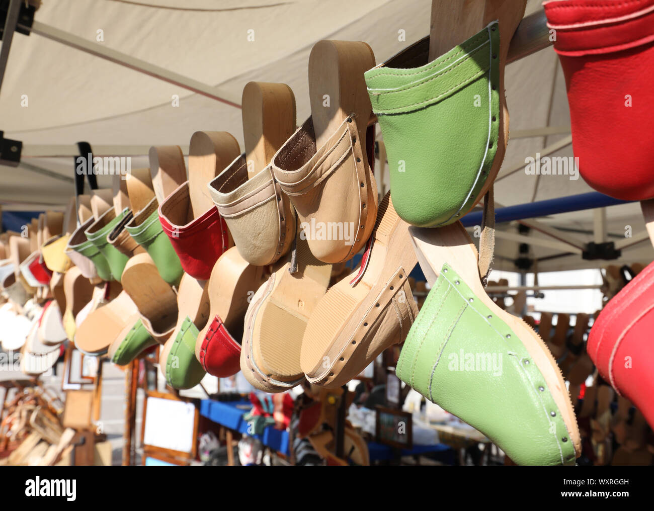 many clogs made by hand with wood and leather for sale at the street ...