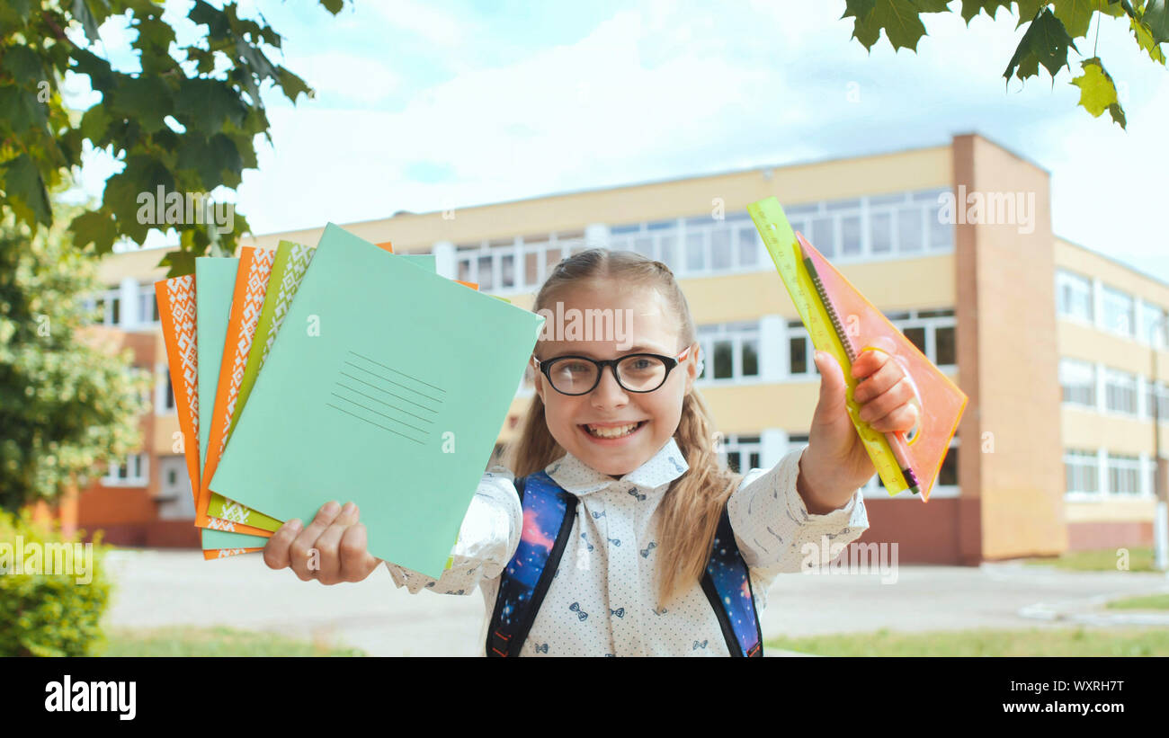 Portrait of a smiling schoolgirl showing notebooks and rulers. Happy ...