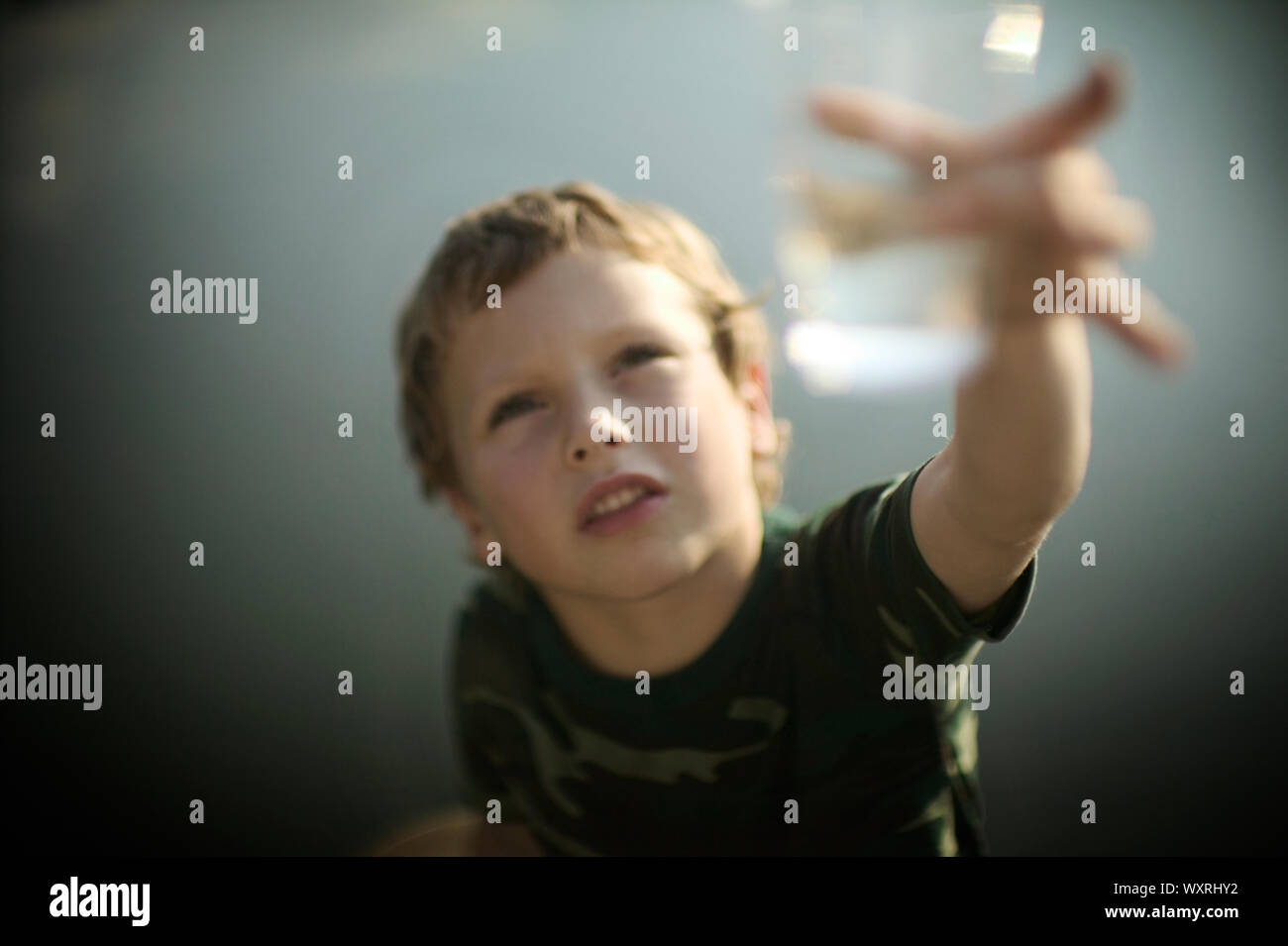 Boy reaching with cup in hand Stock Photo - Alamy