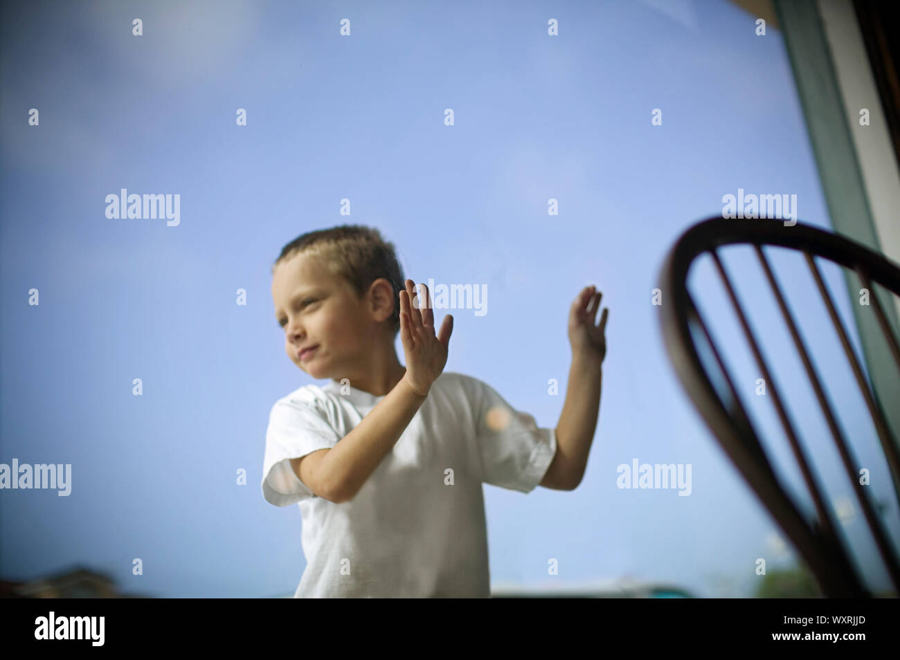 Young boy pressing his hands against a glass window Stock Photo - Alamy