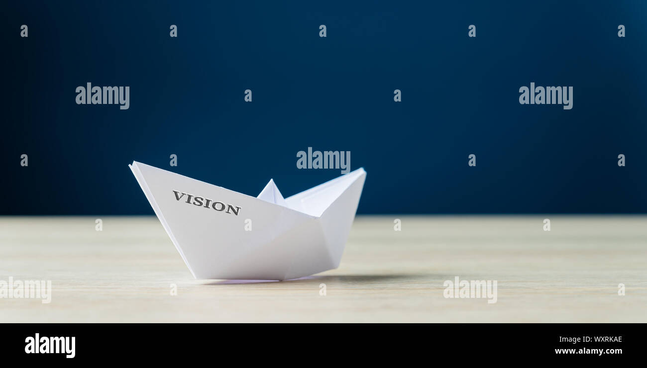 Paper made origami boat with the word Vision on it. Over navy blue ...