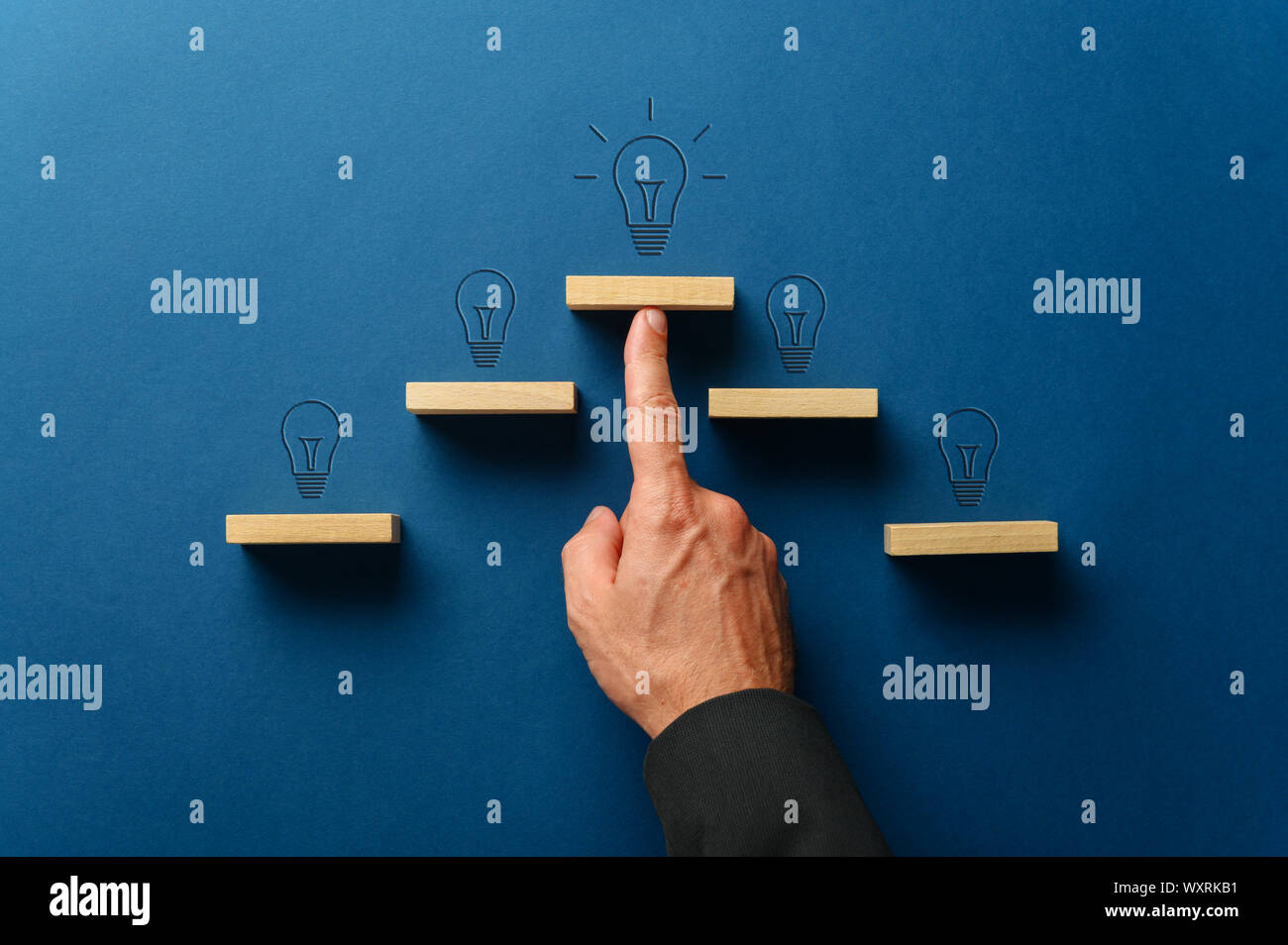 Male finger supporting the top wooden peg in a pyramid shaped stairway ...