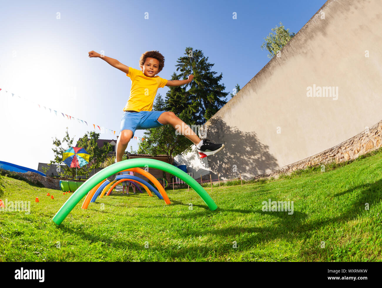 Happy cute boy jump over barriers on playground Stock Photo - Alamy