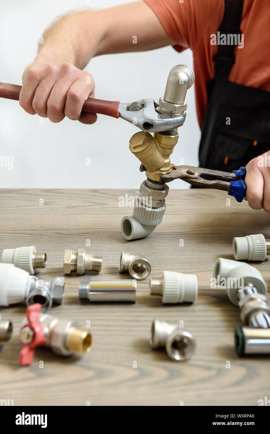 A worker is connecting elements of the plumbing with the adjustable ...