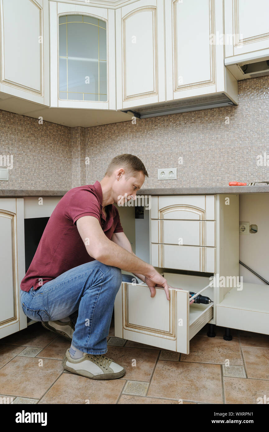 Installation of kitchen furniture. The man is fixing the drawer in a ...