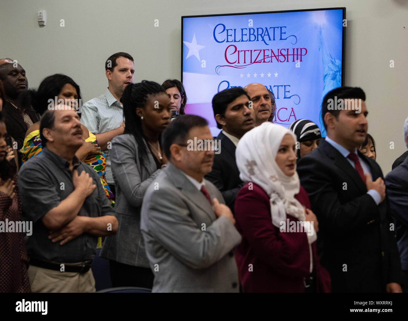 People stand for the pledge of allegiance as they prepare to take the ...