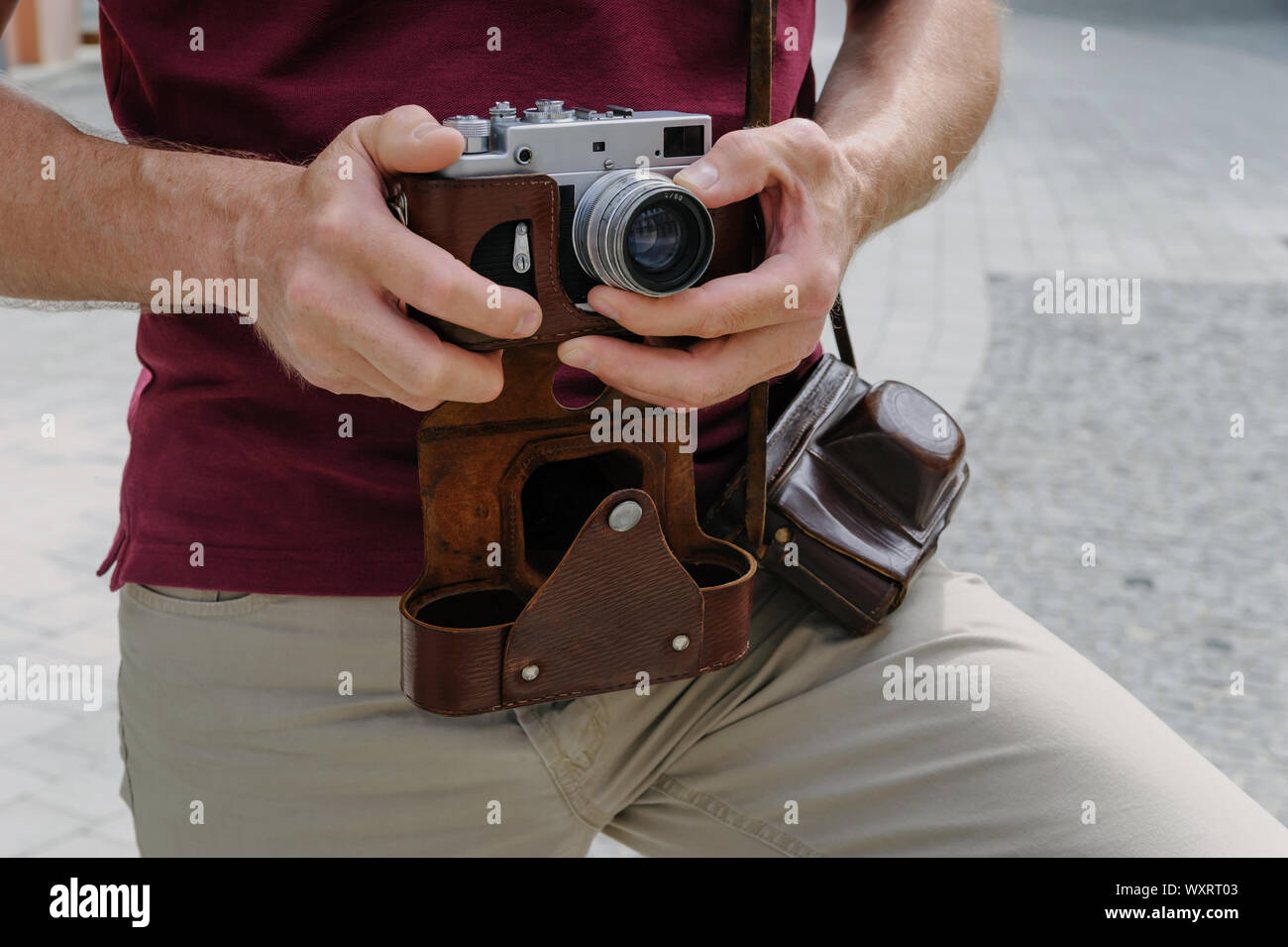 A man is holding a vintage camera. One of his hand is setting the lens ...