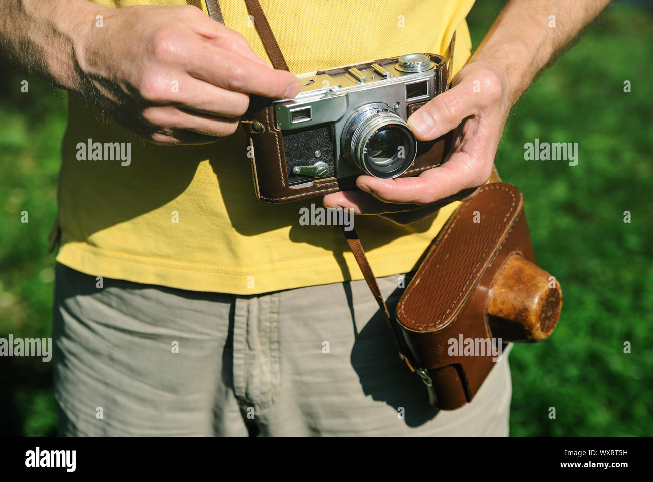 A man is holding a vintage camera. One of his hand is setting the lens ...