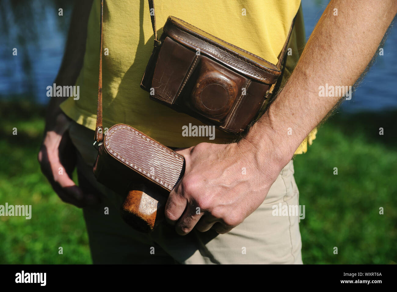 A man has two vintage photo cameras in leather cases. One camera holds ...