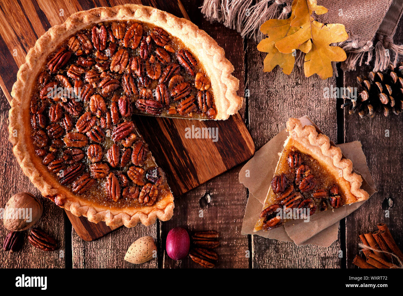 Autumn pecan pie, overhead table scene with cut slice on a rustic wood ...