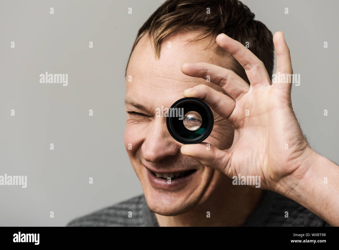 The man is holding and looking through the lens Stock Photo - Alamy