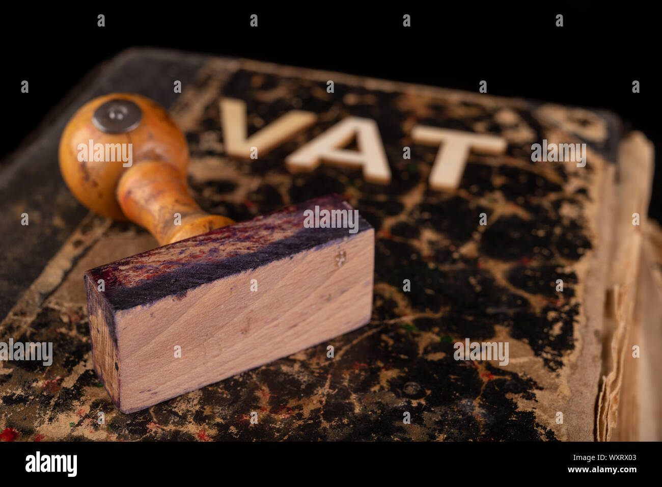 Vat inscription on the old book and stamp. Office accessories on a dark ...