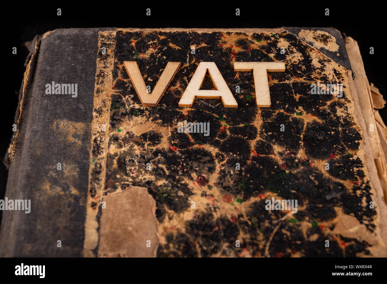 The inscription Vat on the old book. Office accessories on a dark table ...