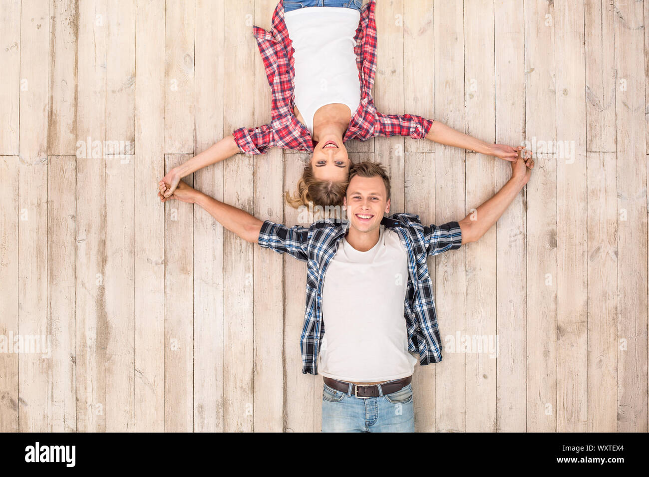 Freestyle. Young man and woman upside down lying on floor holding hands ...