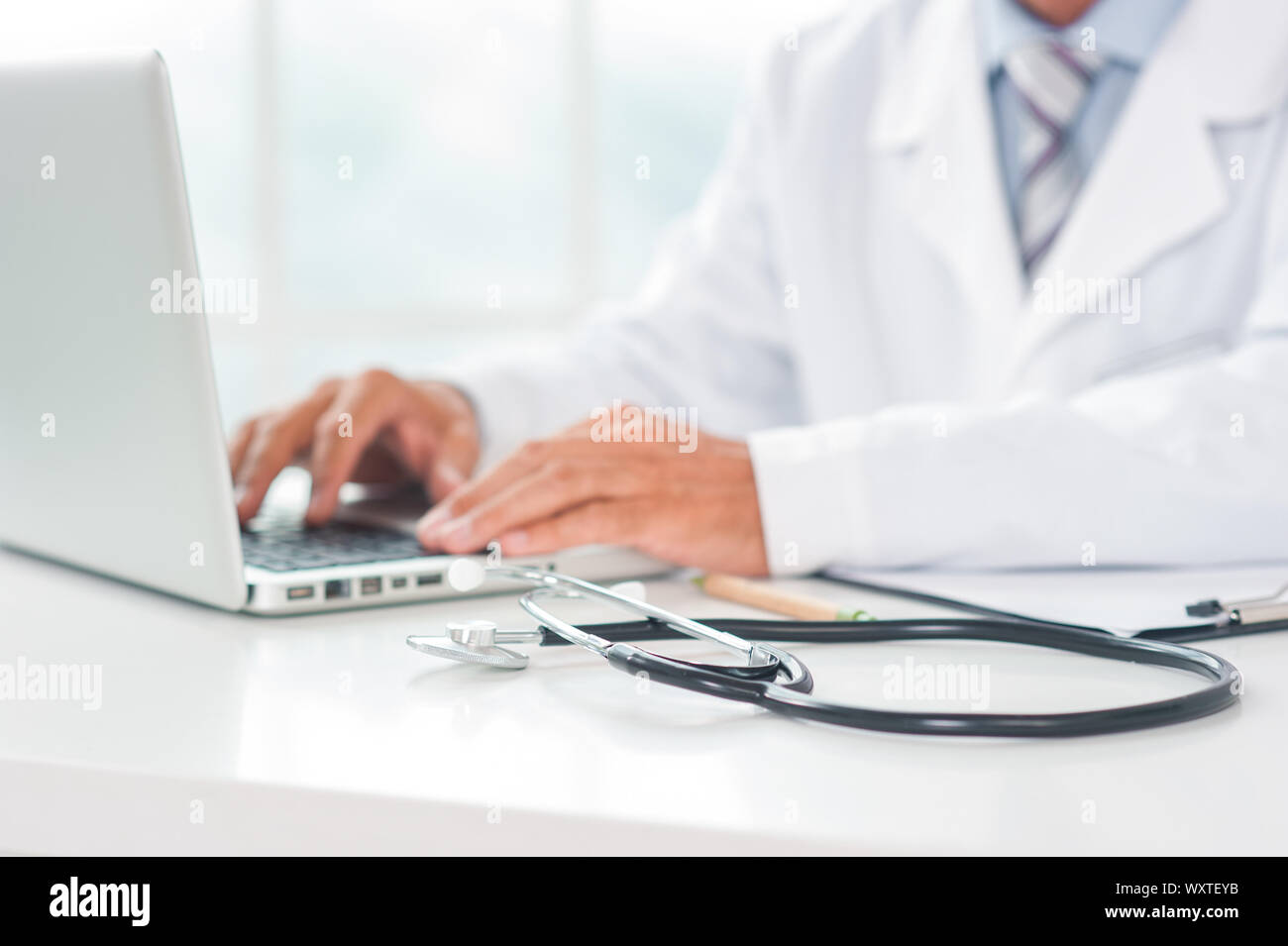 Senior doctor at his office in hospital working close-up blurred using ...