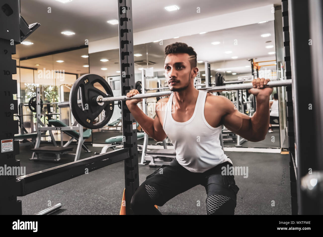 Man at the gym. Execute exercise squatting with weight, in gym Stock ...