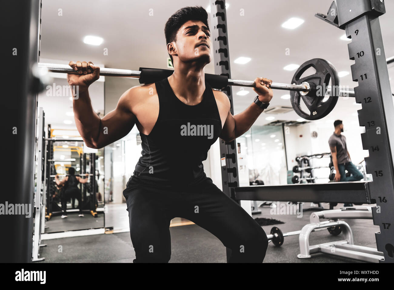 Man at the gym. Execute exercise squatting with weight, in gym Stock ...