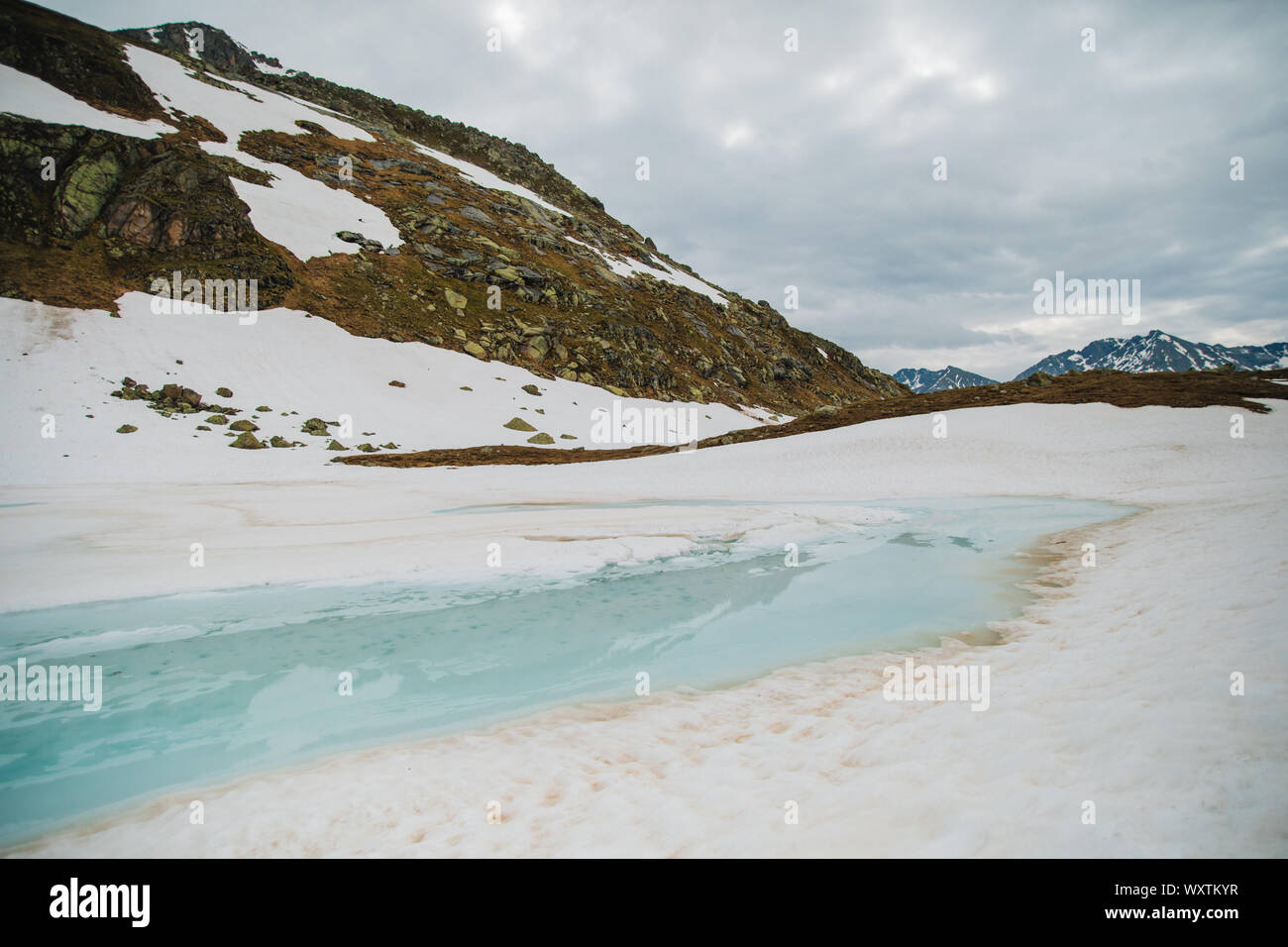 The snow is melting from the mountains and flows in creek, close up ...