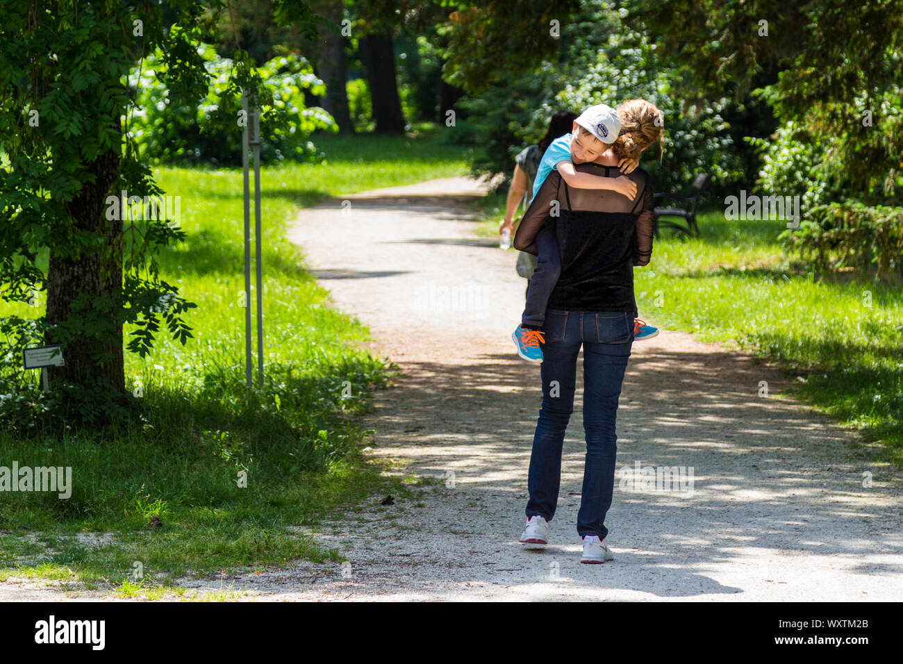 Teenage girl sister carrying her little boy child brother on footpath ...