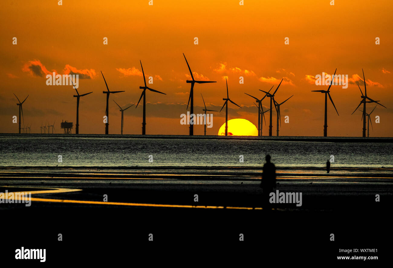 The sun sets behind Burbo Bank wind farm and 'Another Place', an art ...