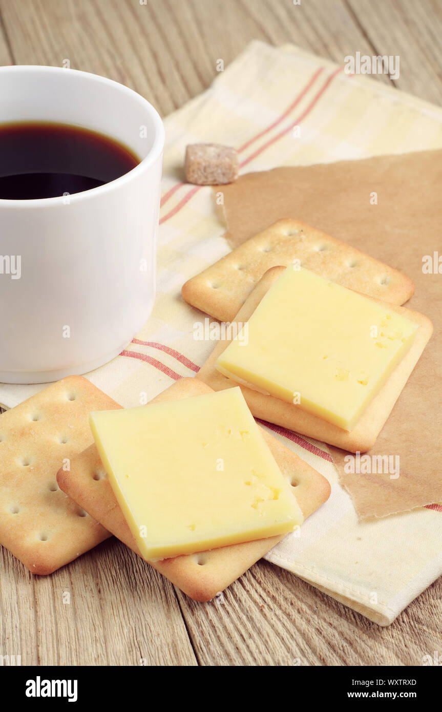 Coffee cup and tasty cracker cookies with cheese and on wooden table ...