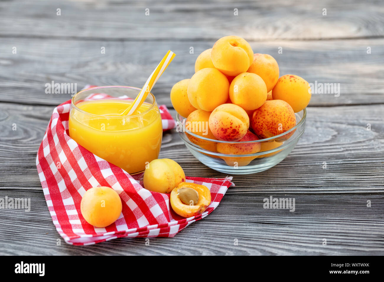 Apricot juice in glass cup with straw and apricots in bowl on wooden ...