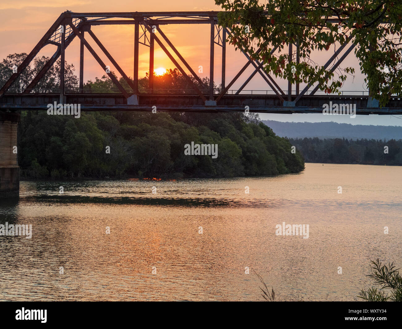 sunset over river behind railroad bridge Stock Photo - Alamy