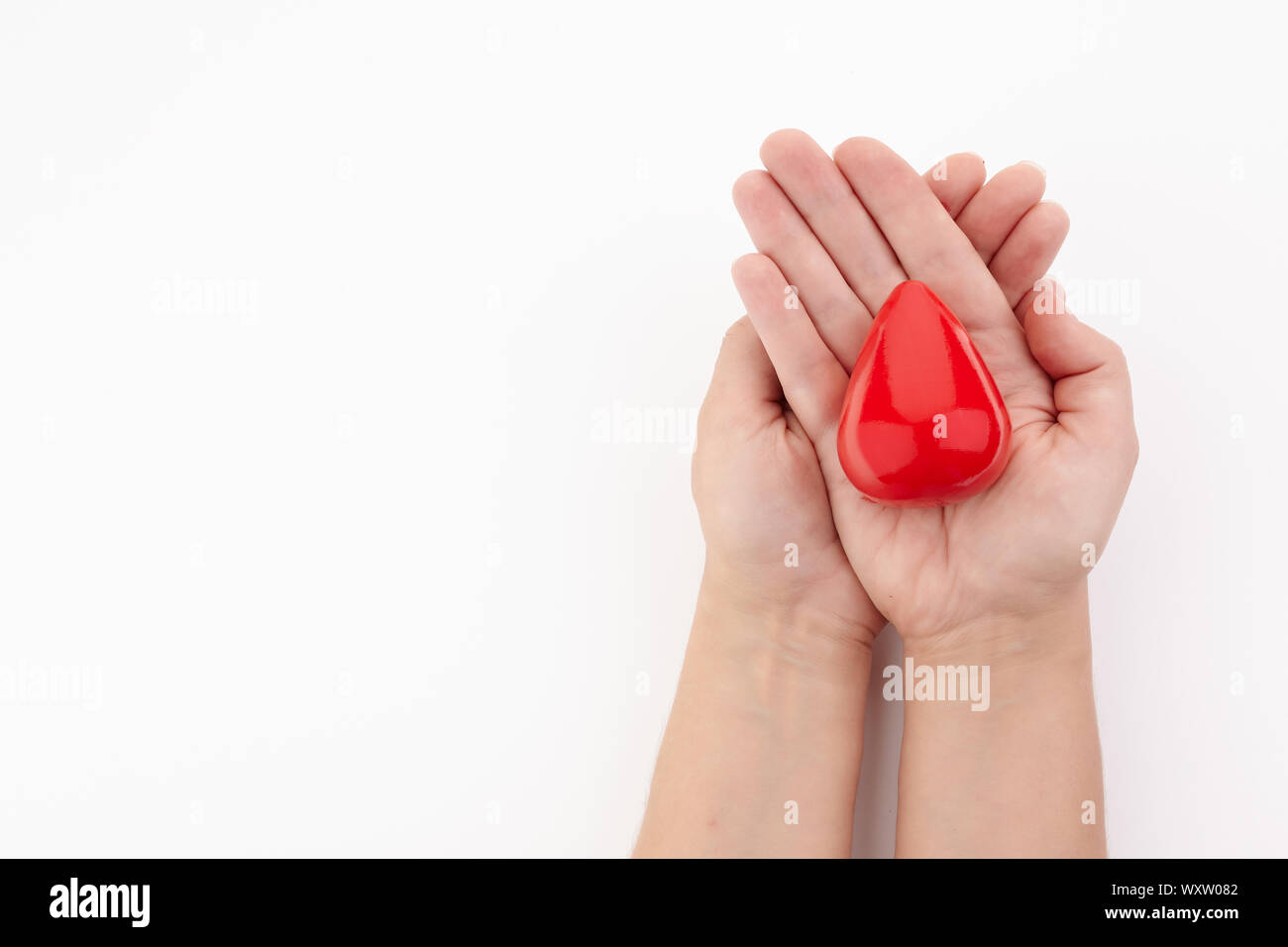 Two hands holding red blood drop on white background. Give blood ...