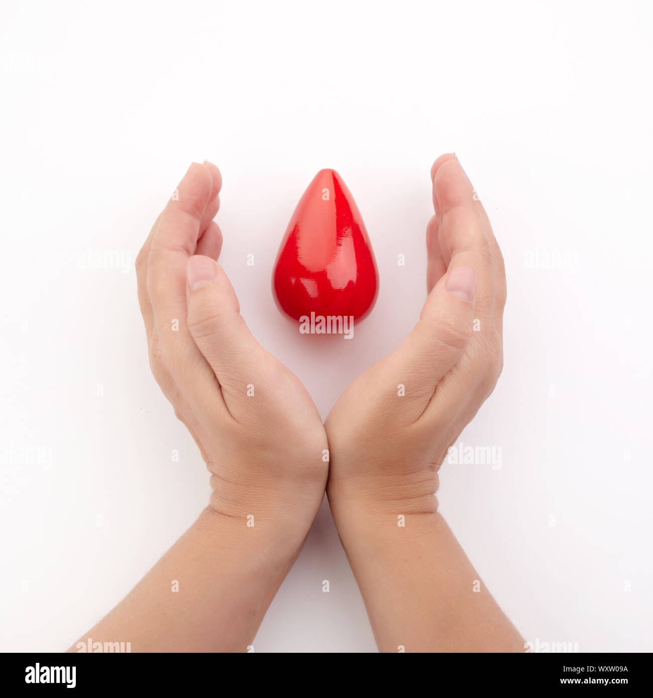 Two hands holding red blood drop on white background. Give blood ...