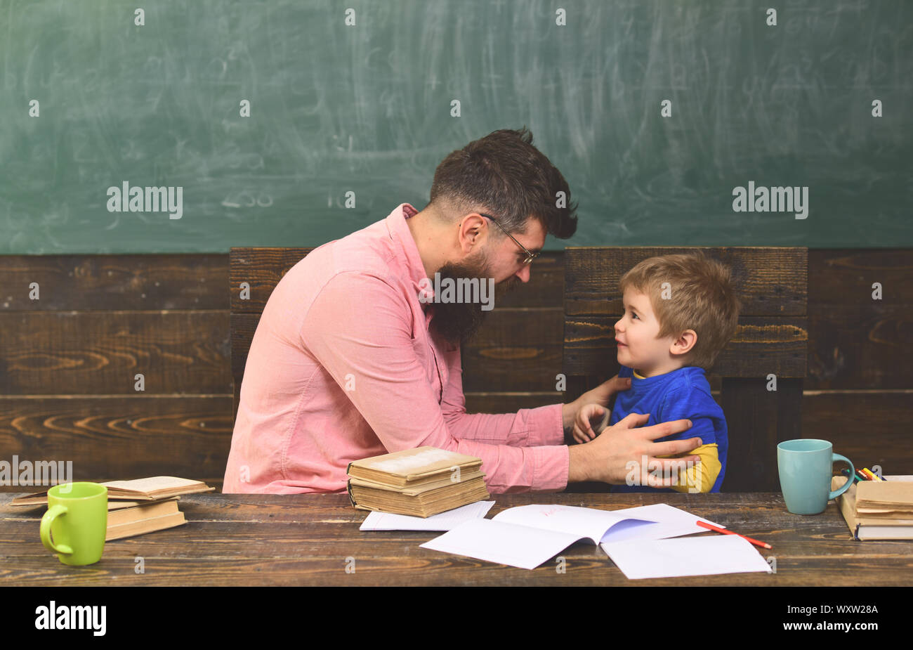 Male teacher explaining something to the boy. Side view bearded man in ...
