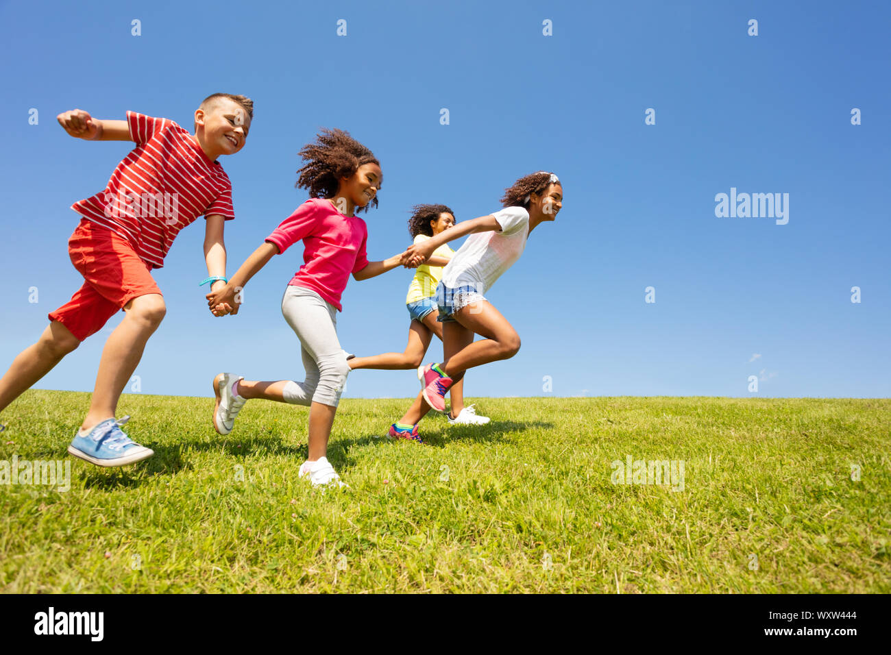 Diverse group of happy kids run in park hold hands Stock Photo - Alamy