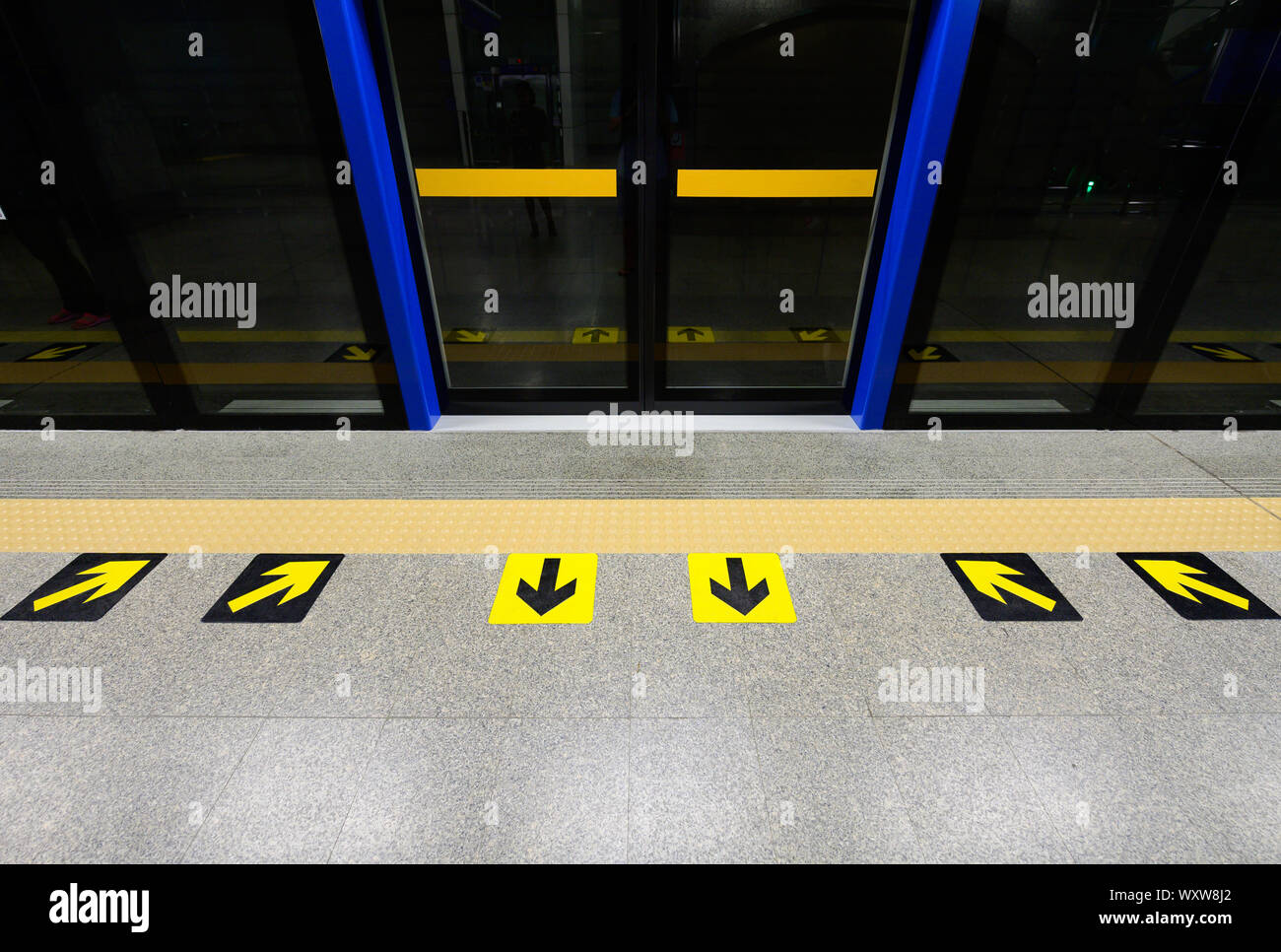 Yellow arrow marks on the floor of subway platform Stock Photo - Alamy