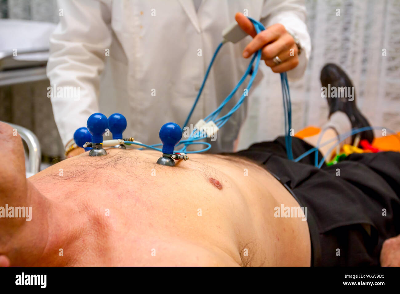 Cardiologist is attaching vacuum sensors to elder patient for recording ...